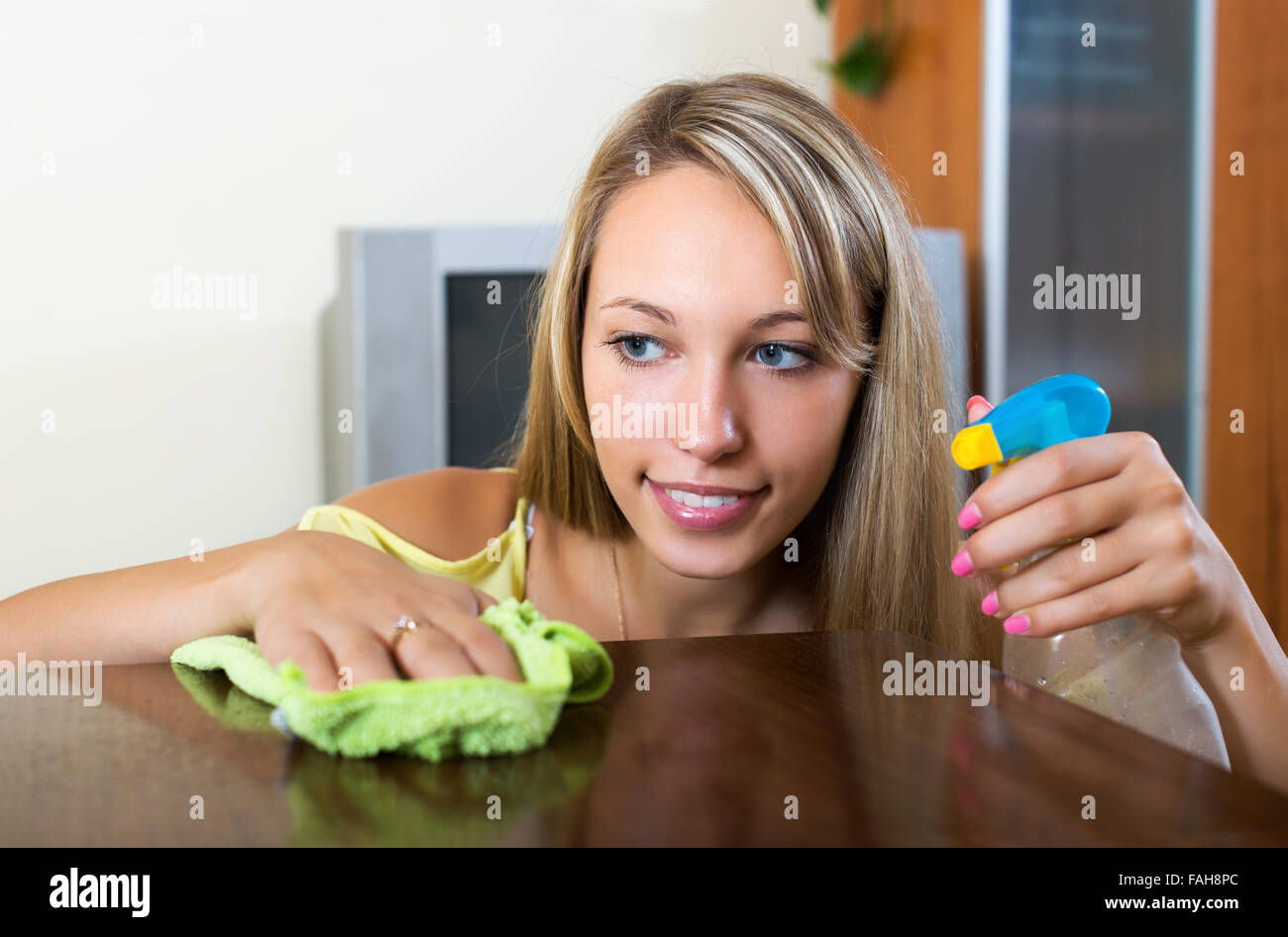 Young positive girl dusting table during chamber work Stock Photo - Alamy