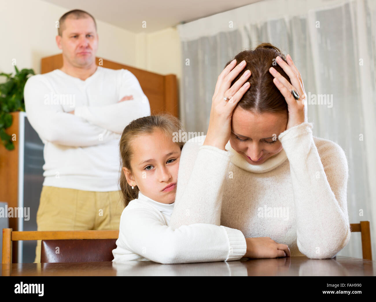 daughter gives solace to crying mother at home and angry father Stock ...