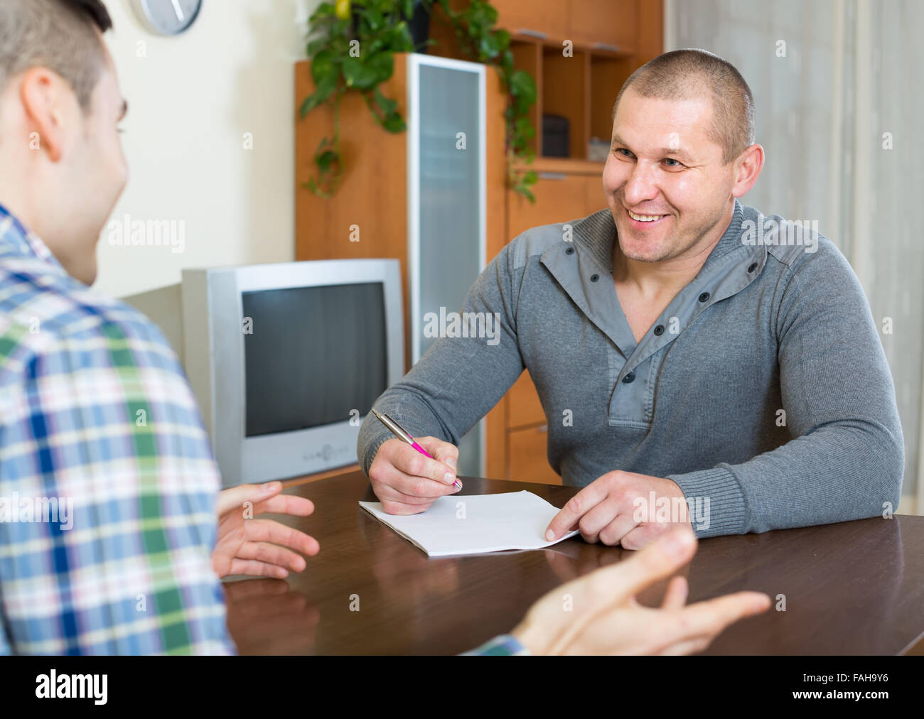 Male agent explaining to client terms of life insurance at home Stock ...