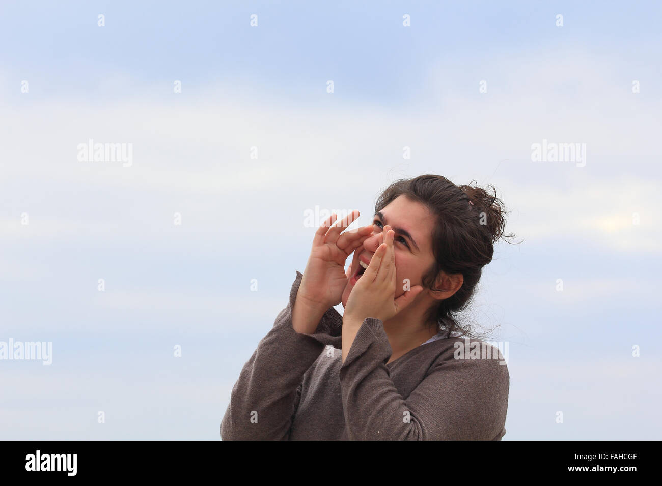 Young woman shouting, with hands on mouth Stock Photo - Alamy