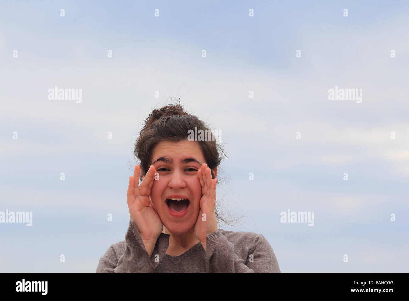 Young woman shouting, with hands on mouth Stock Photo - Alamy
