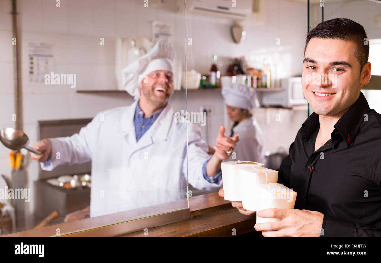 Young smiling handsome guy purchasing fast food in cardboard box at ...
