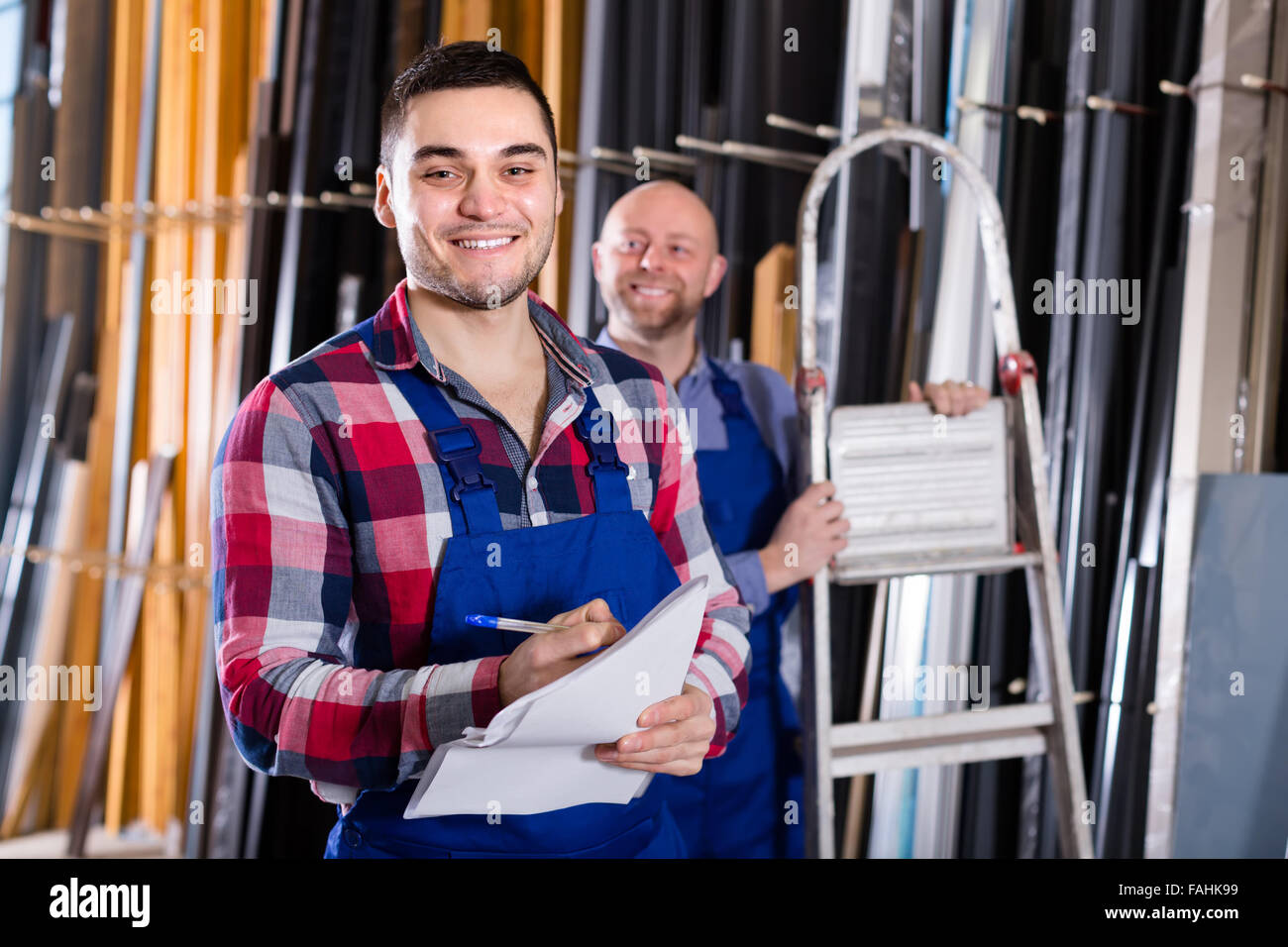 Two happy production workers in coverall with different PVC window ...