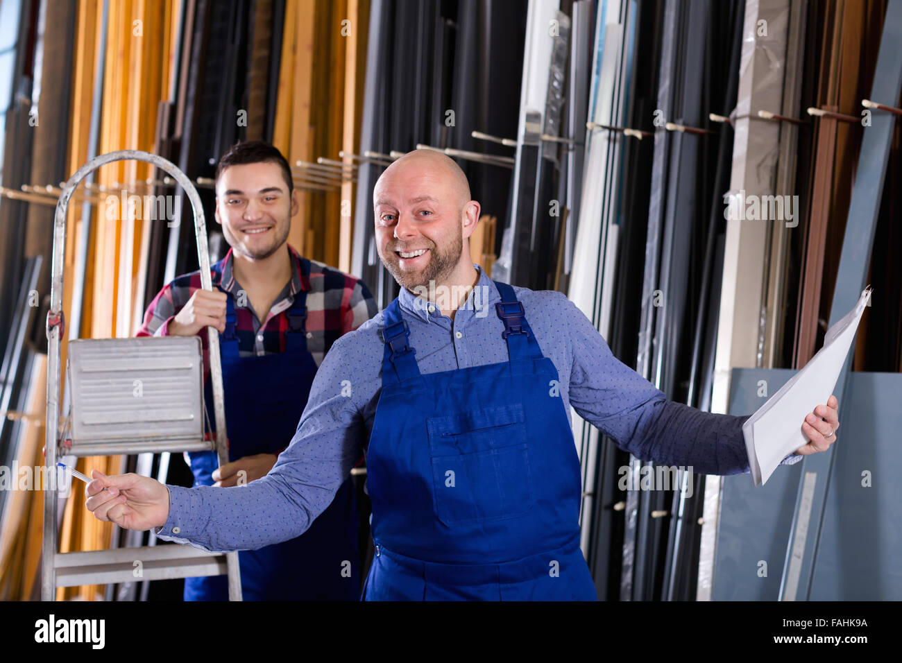 Careful worker in coverall operating in lathe, his boss with papers ...