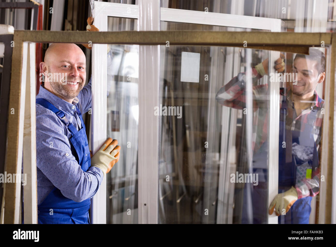 Couple of workmen inspecting windows at workshop Stock Photo - Alamy