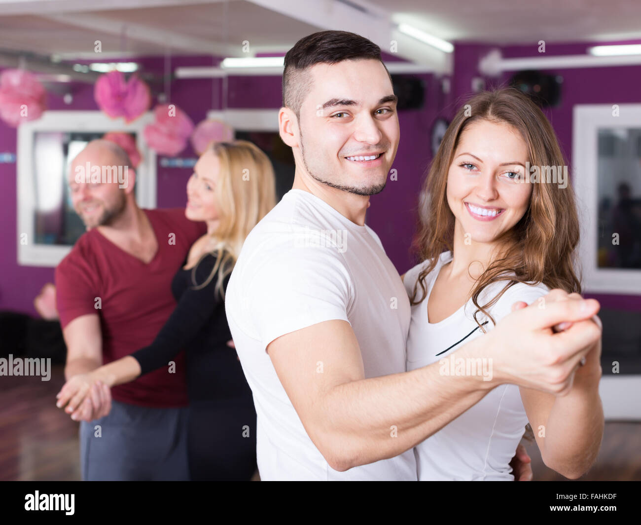 Group of smiling positive young adults dancing at dance class. Focus on ...