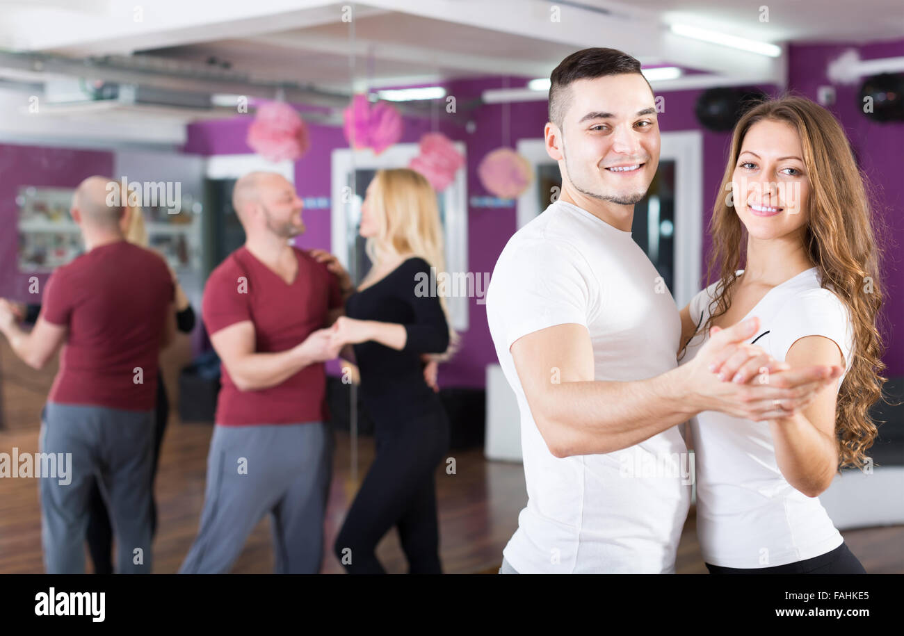 Group of smiling young adults dancing salsa at dance class. Focus on ...