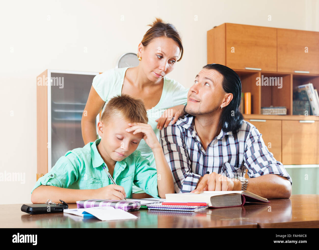 couple with teenager son doing homework in home interior Stock Photo ...