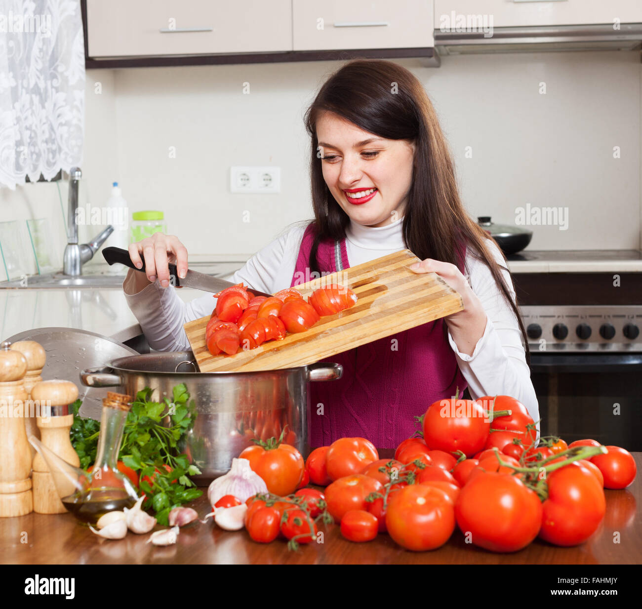 Smiling woman cooking with tomatoes in kitchen Stock Photo - Alamy