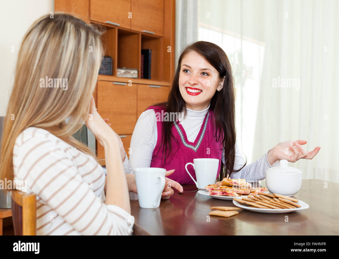 two happy women drinking tea and gossiping in home Stock Photo - Alamy