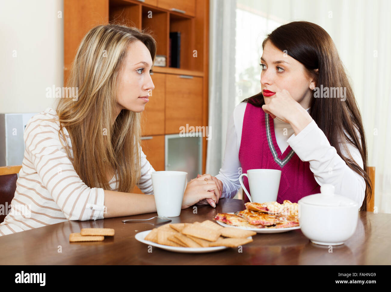 Young woman comforting friend in home Stock Photo - Alamy