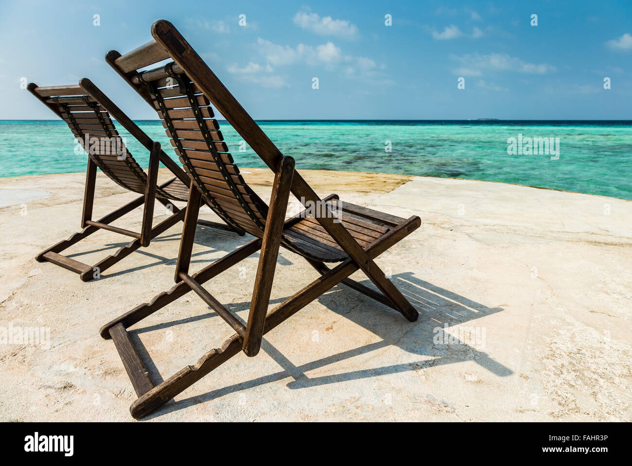 Two deck chairs looking out to sea on a sea defence groin at the island ...