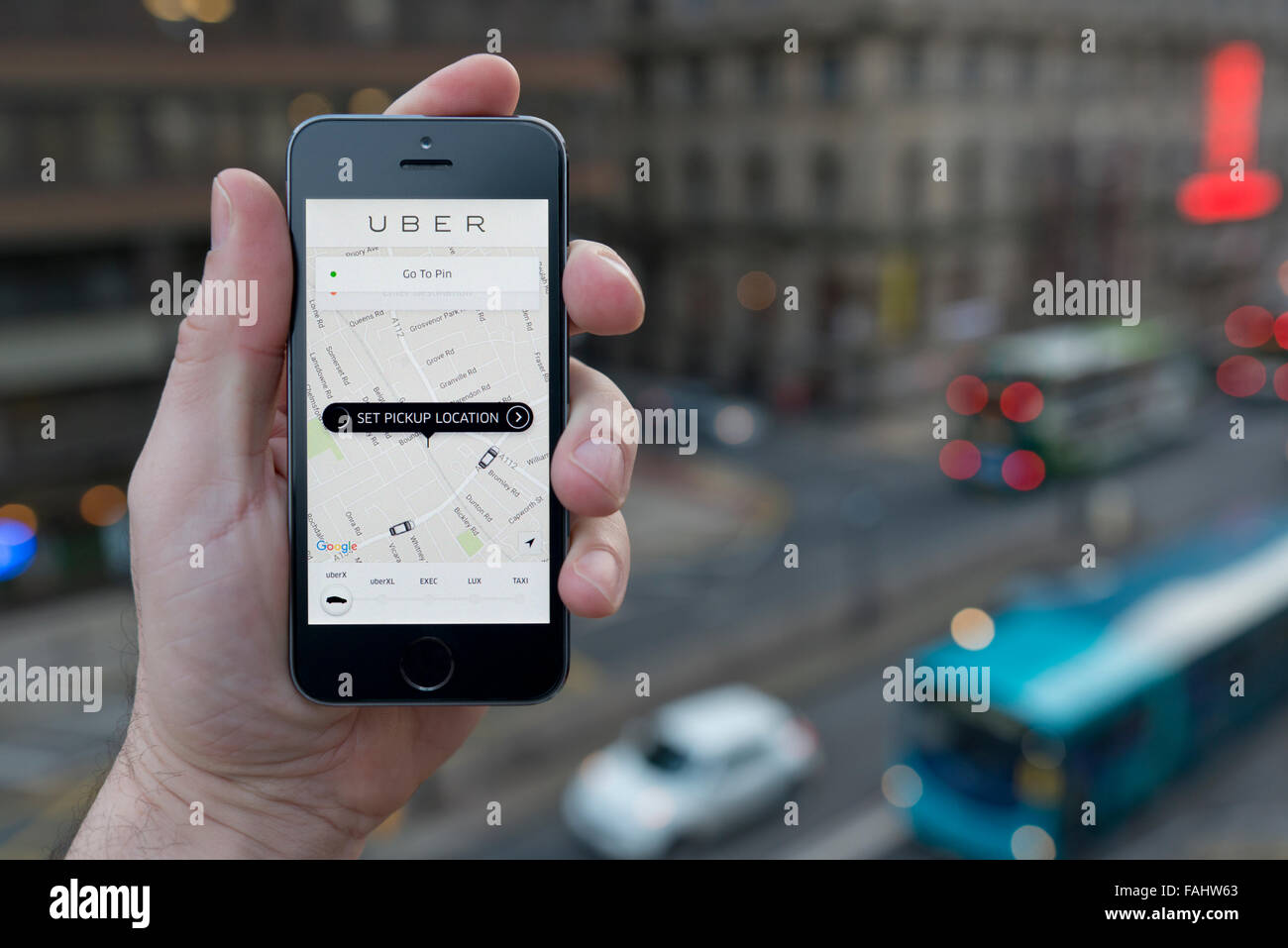 A man uses the Uber taxi smartphone app while stood in a tall building ...