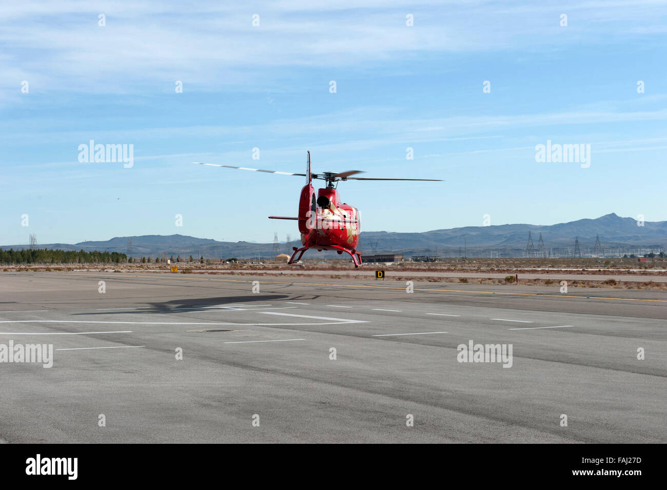 A red helicopter taking off into the cloudless blue sky on a sunny warm ...
