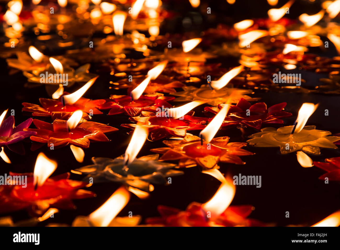 Close focus onto bright candle floating on pool of hot oil in public ...