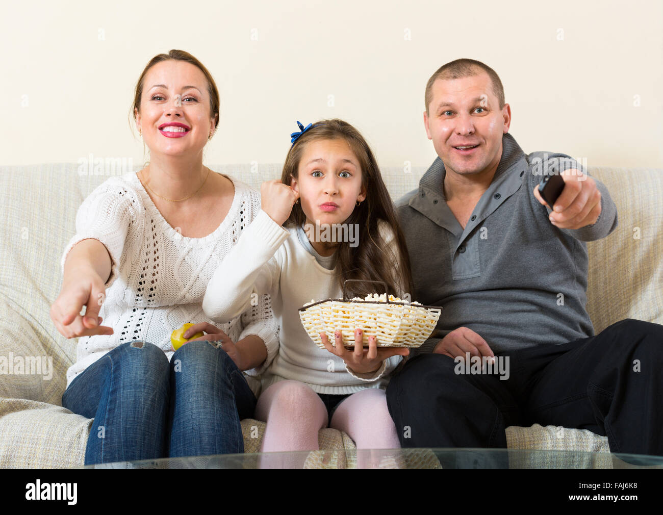 Parents and cute girl watching TV show together indoors. Focus on girl ...