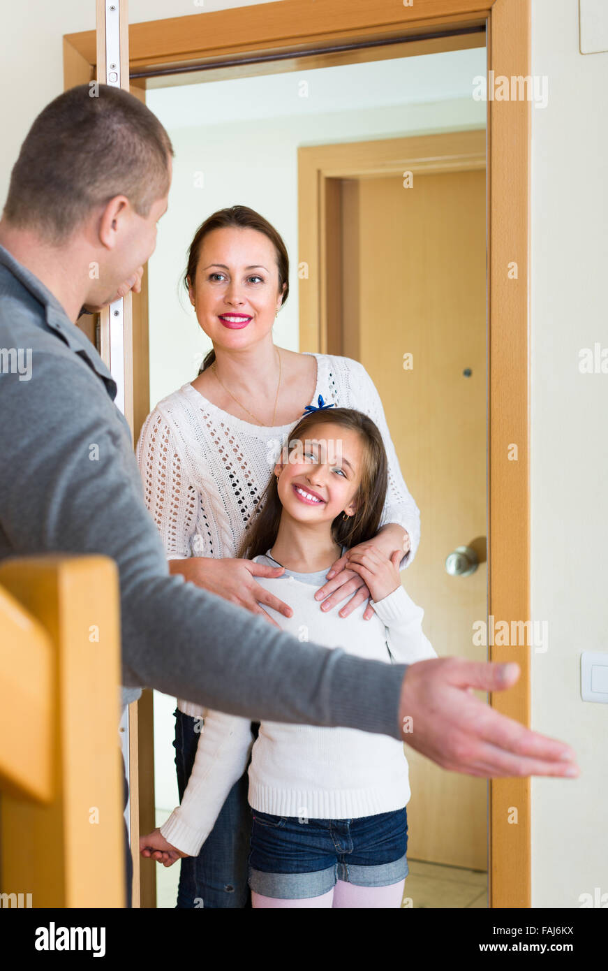 Happy man standing at doorway and inviting guests to come inside. Focus ...