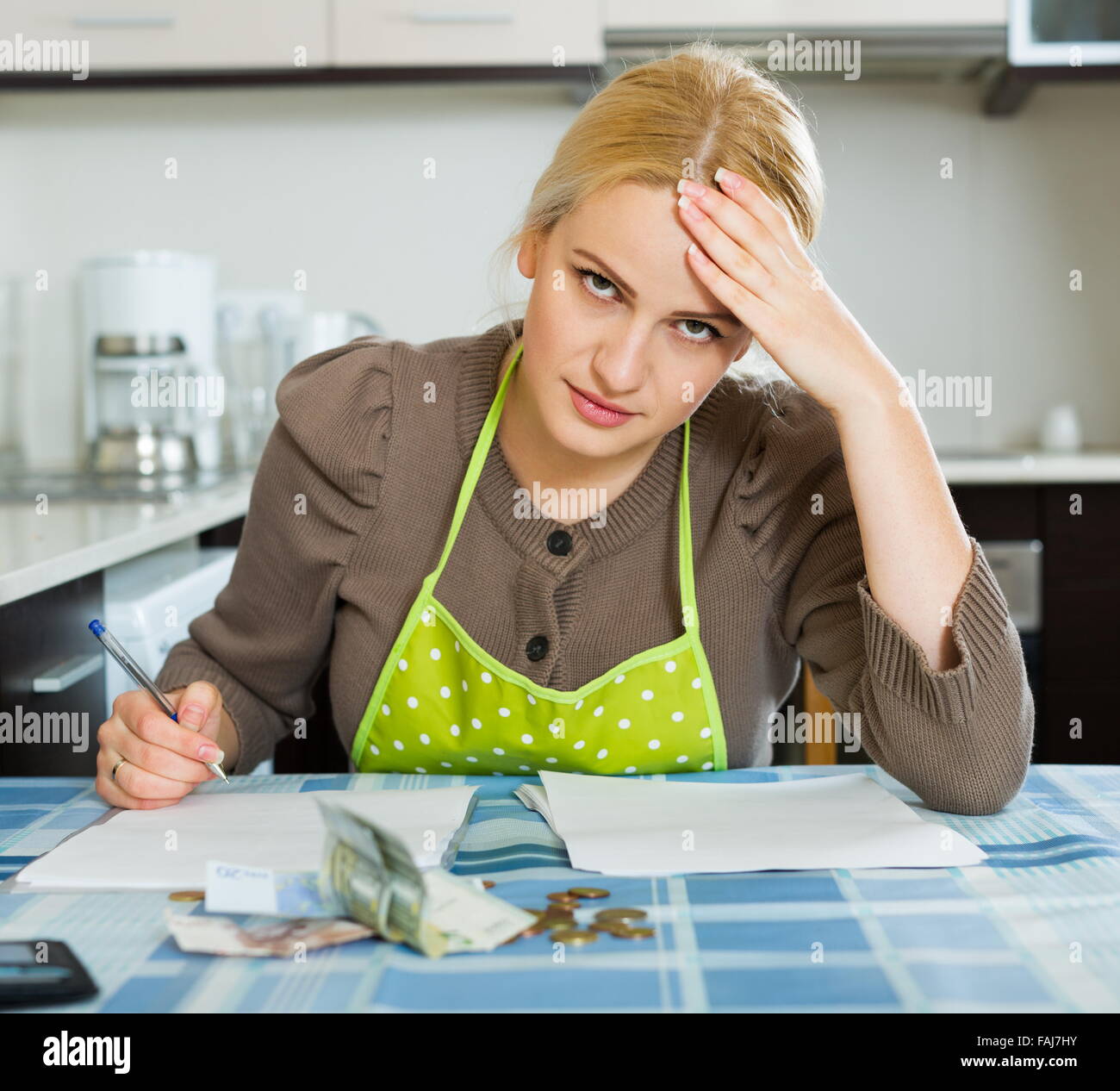 Blond housewife filling in utility payments bills at home Stock Photo ...