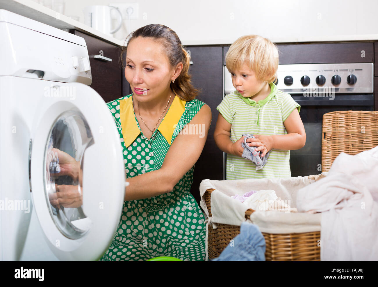 Home laundry. Smiling woman with little child using washing machine at ...