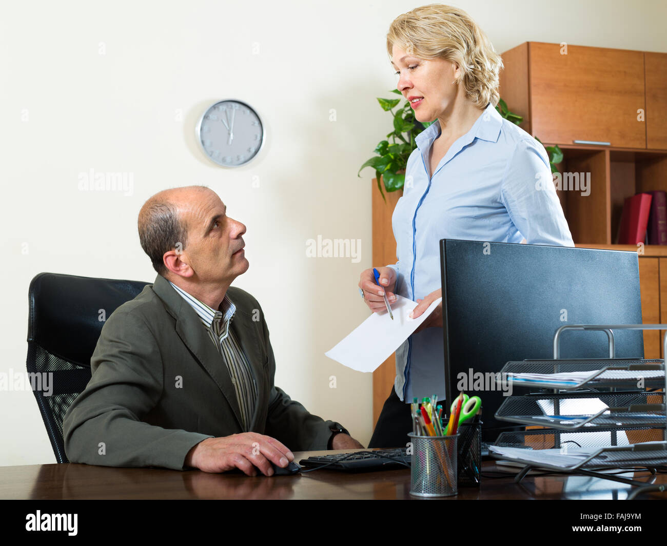 Aged chief listening mature female secretary in office Stock Photo - Alamy