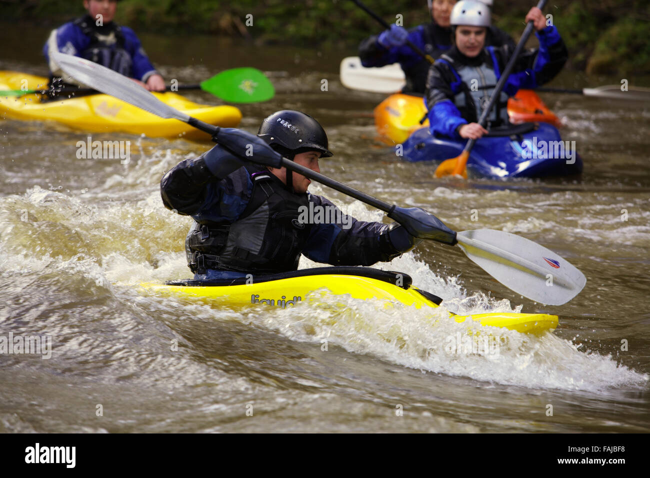 Man paddling yellow kayak through rough water, wearing black helmet ...