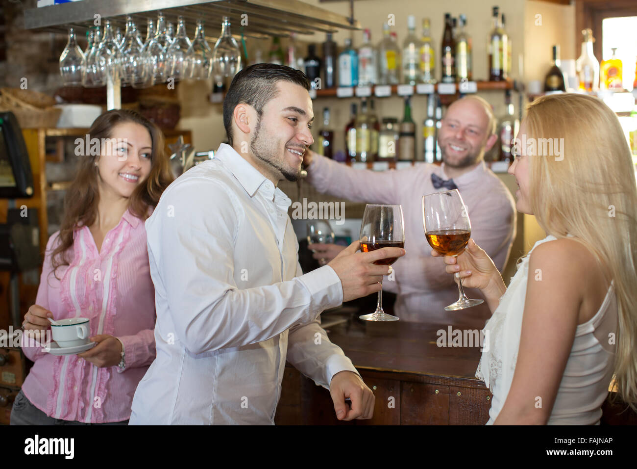 Happy bartender entertaining guests at a bar counter in bar Stock Photo ...