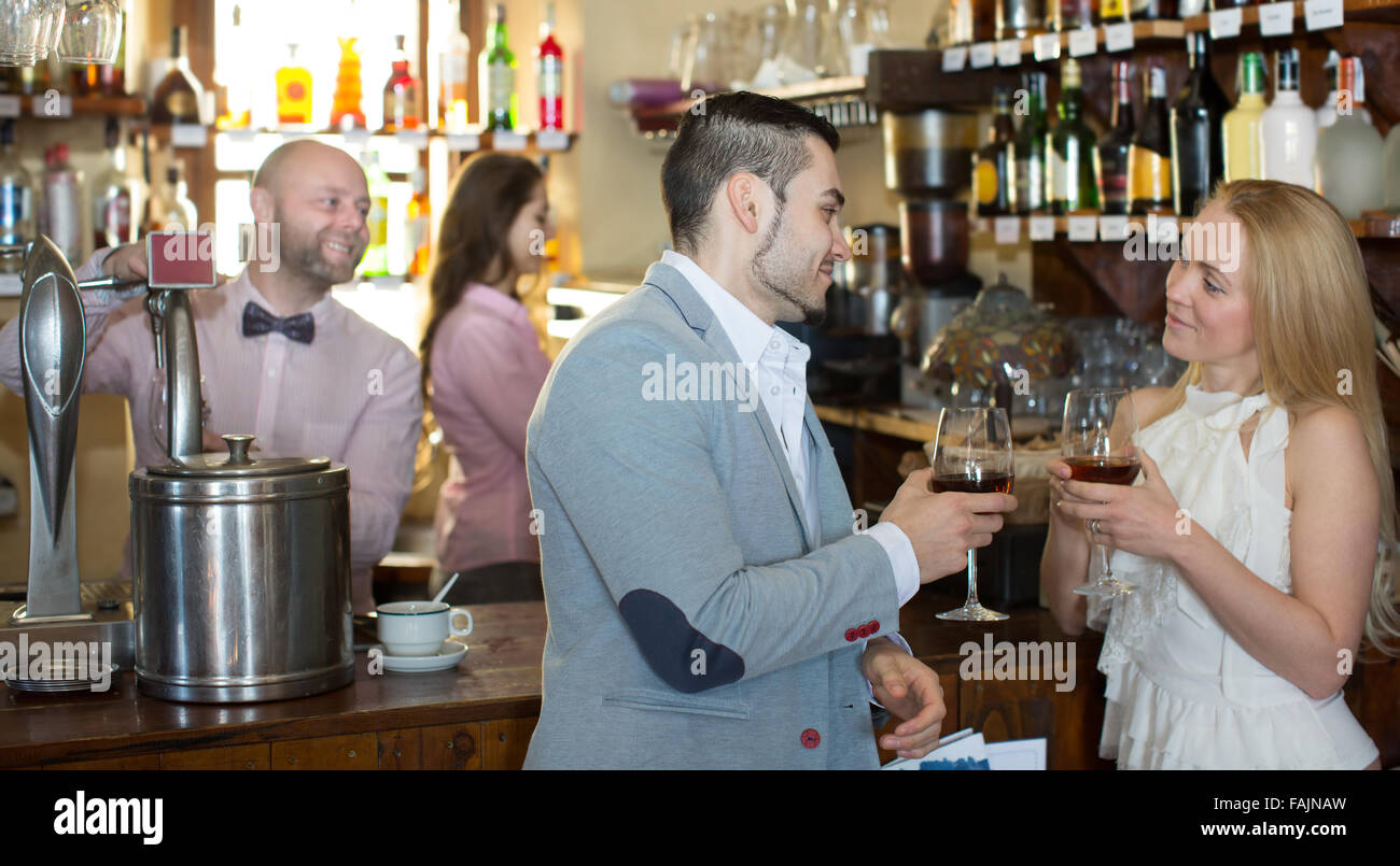 Positive happy bartender entertaining guests at a bar counter in bar ...