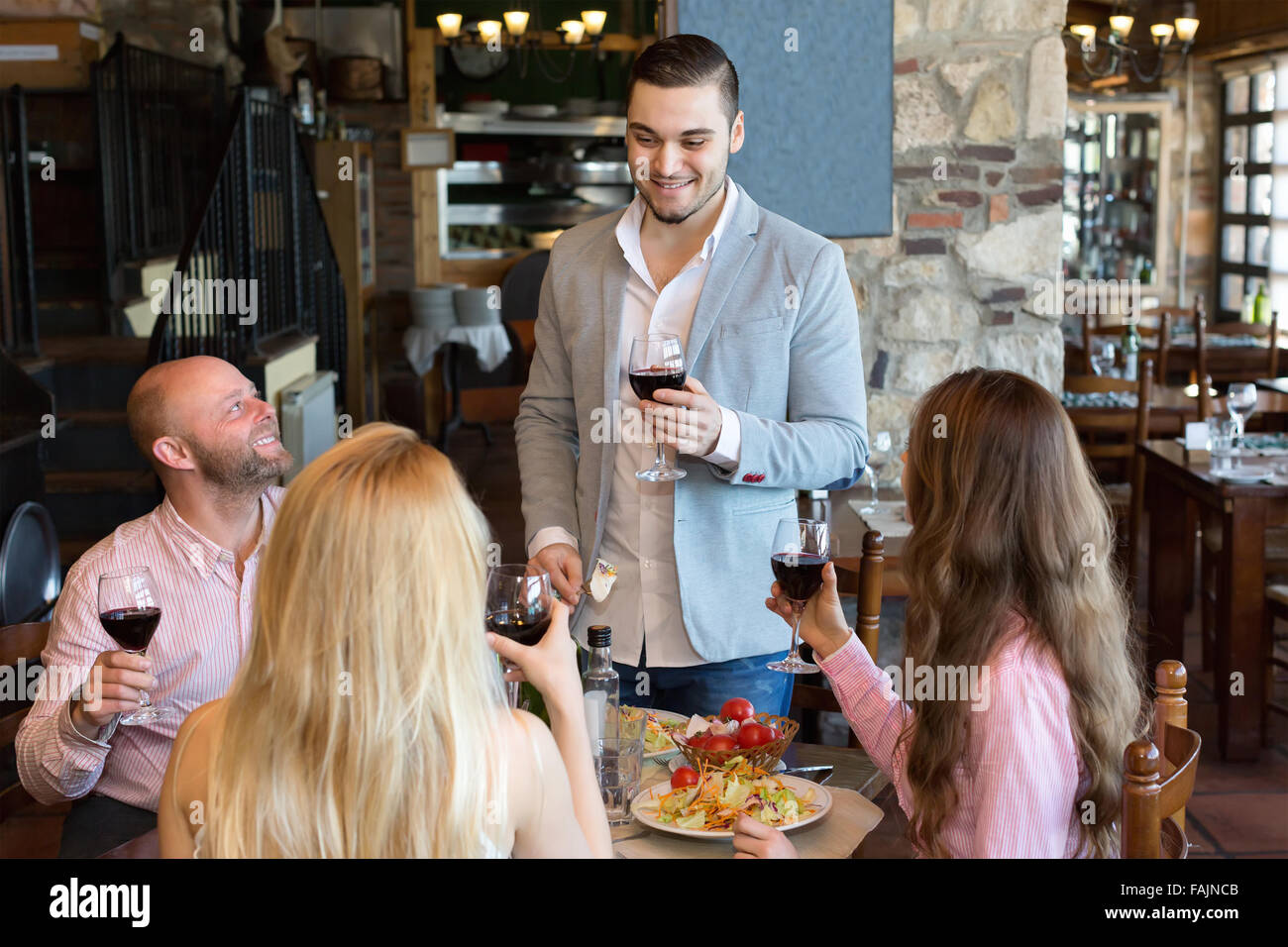 Four relaxed people sitting at restaurant table Stock Photo - Alamy