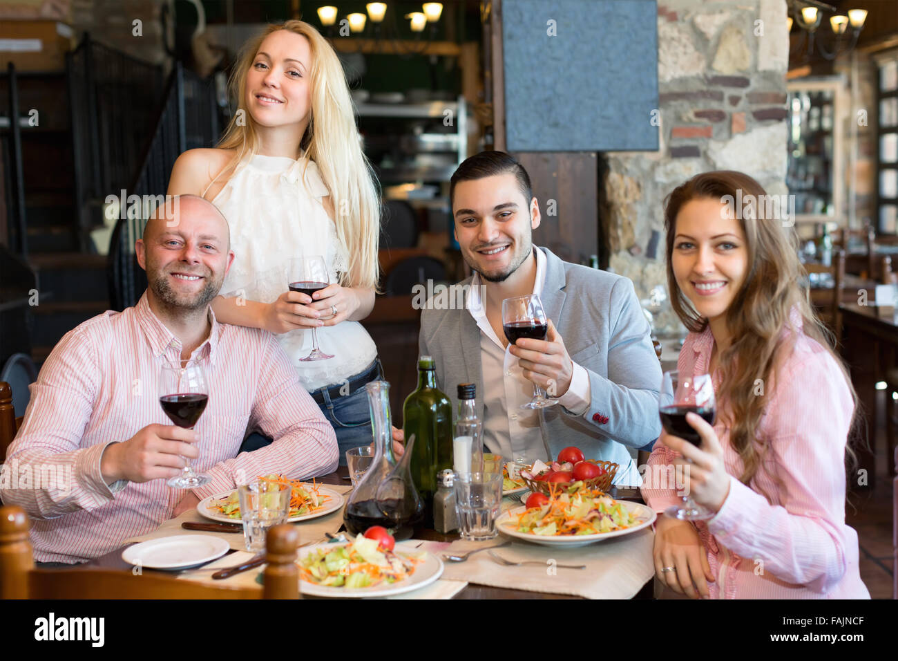 Four cheerful people sitting at restaurant table Stock Photo - Alamy