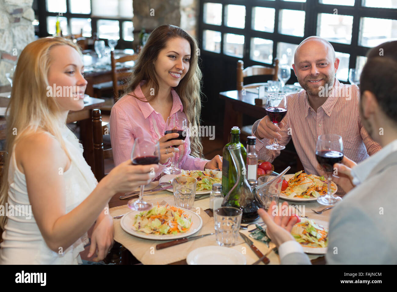 Positive happy young people enjoying food and smiling at tavern Stock ...