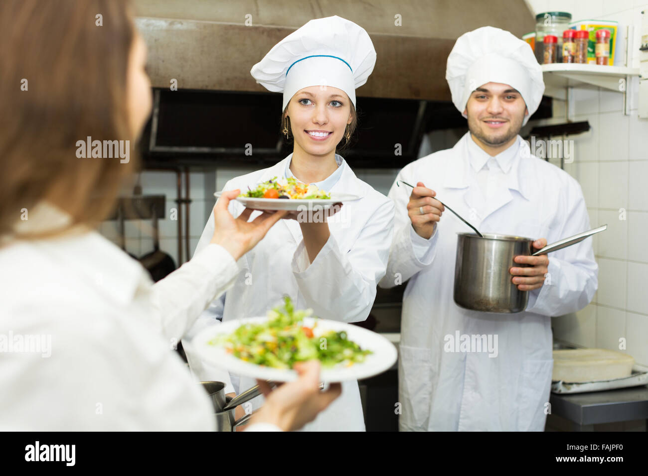 Cook gives to girl waitress plates with prepared meal at restaurant ...