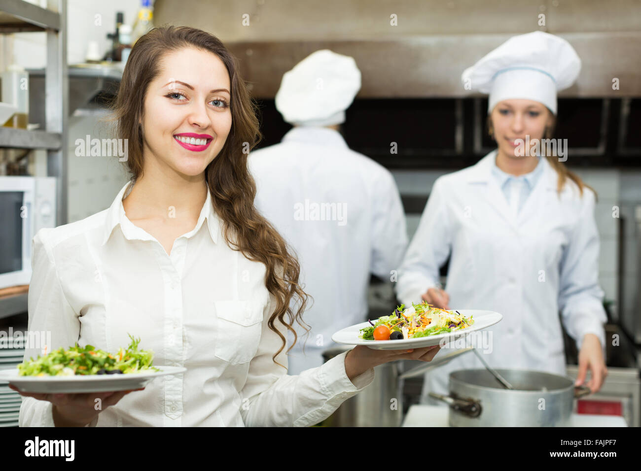 Team of positive chefs and young waiter in restaurant kitchen Stock ...