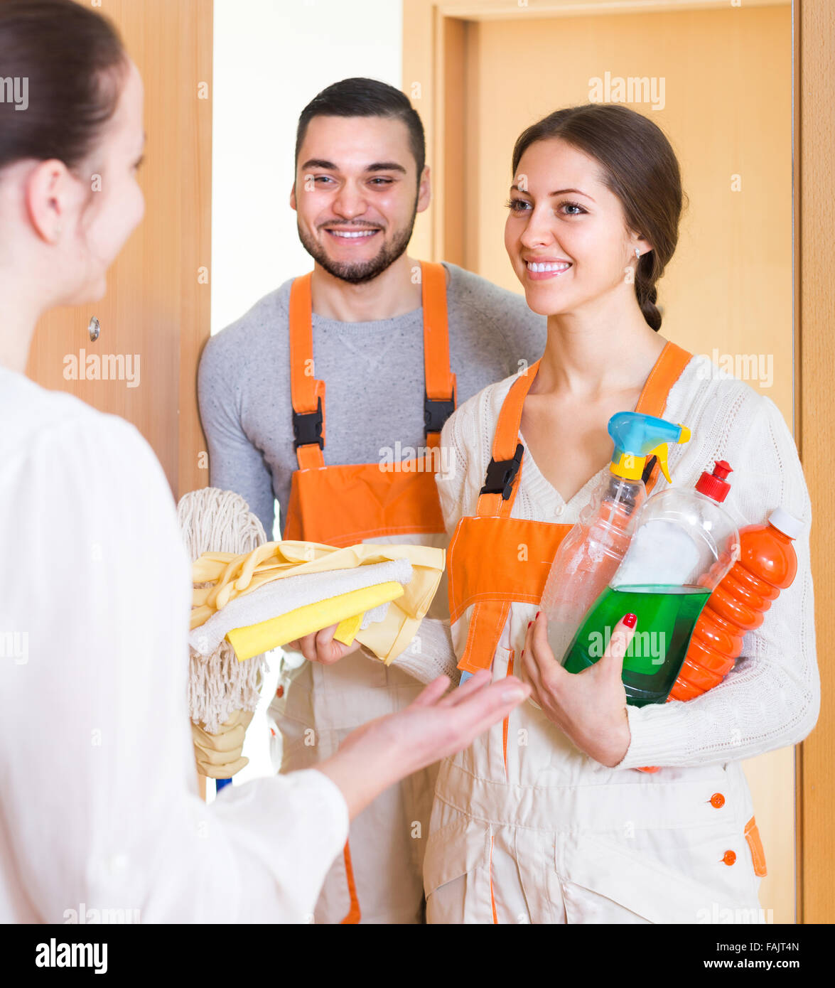 Housewife meeting cleaning crew with equipment at doorway. Focus on ...