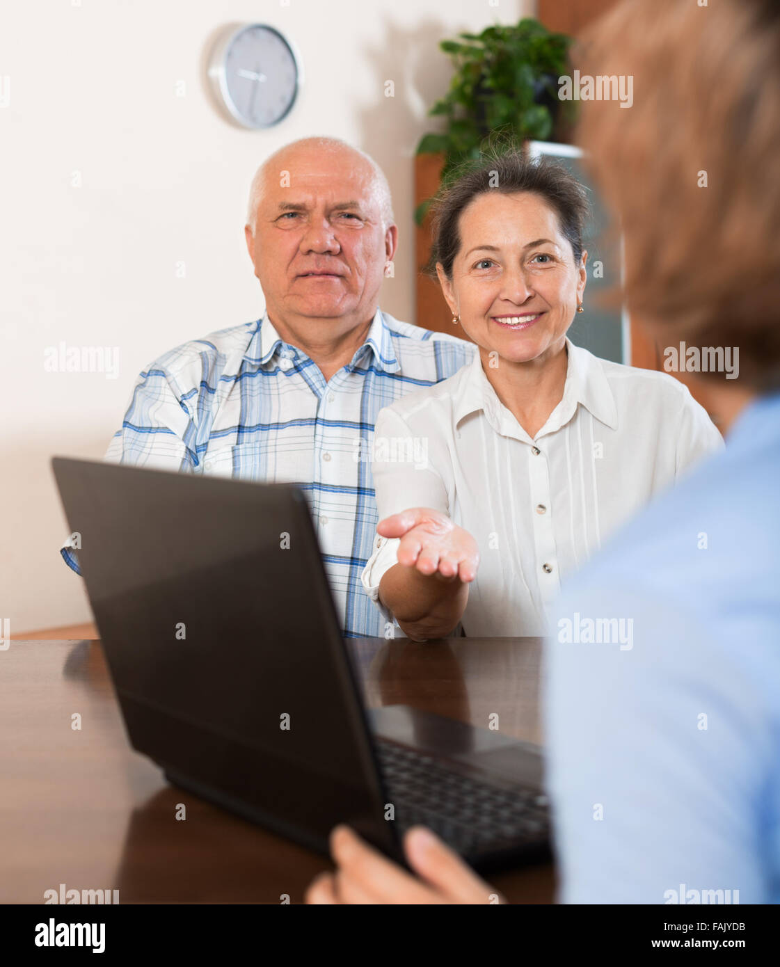Mature couple answer questions of caseworker with notebook in home ...