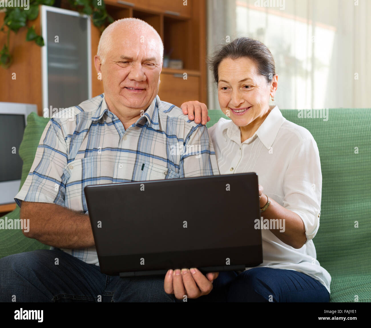 Happy elderly man and mature woman using laptop in room Stock Photo - Alamy