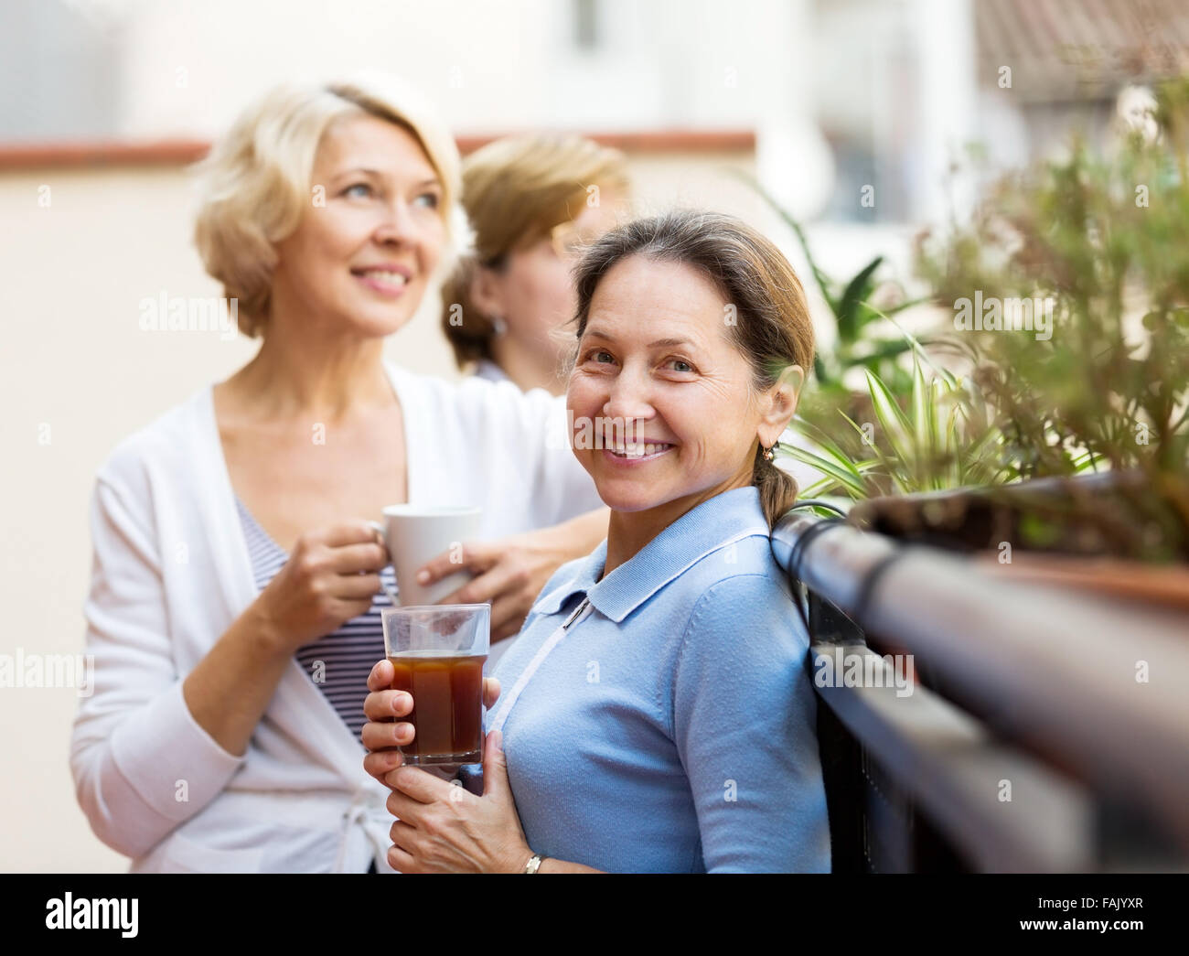 Happy senior female colleagues having lunch break at patio and drinking ...