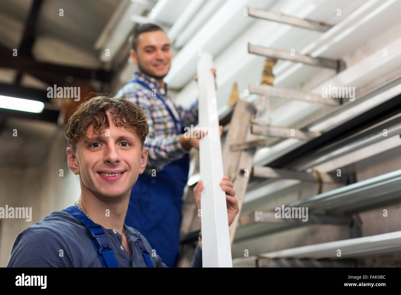 Smiling production workers in uniform with different PVC window ...