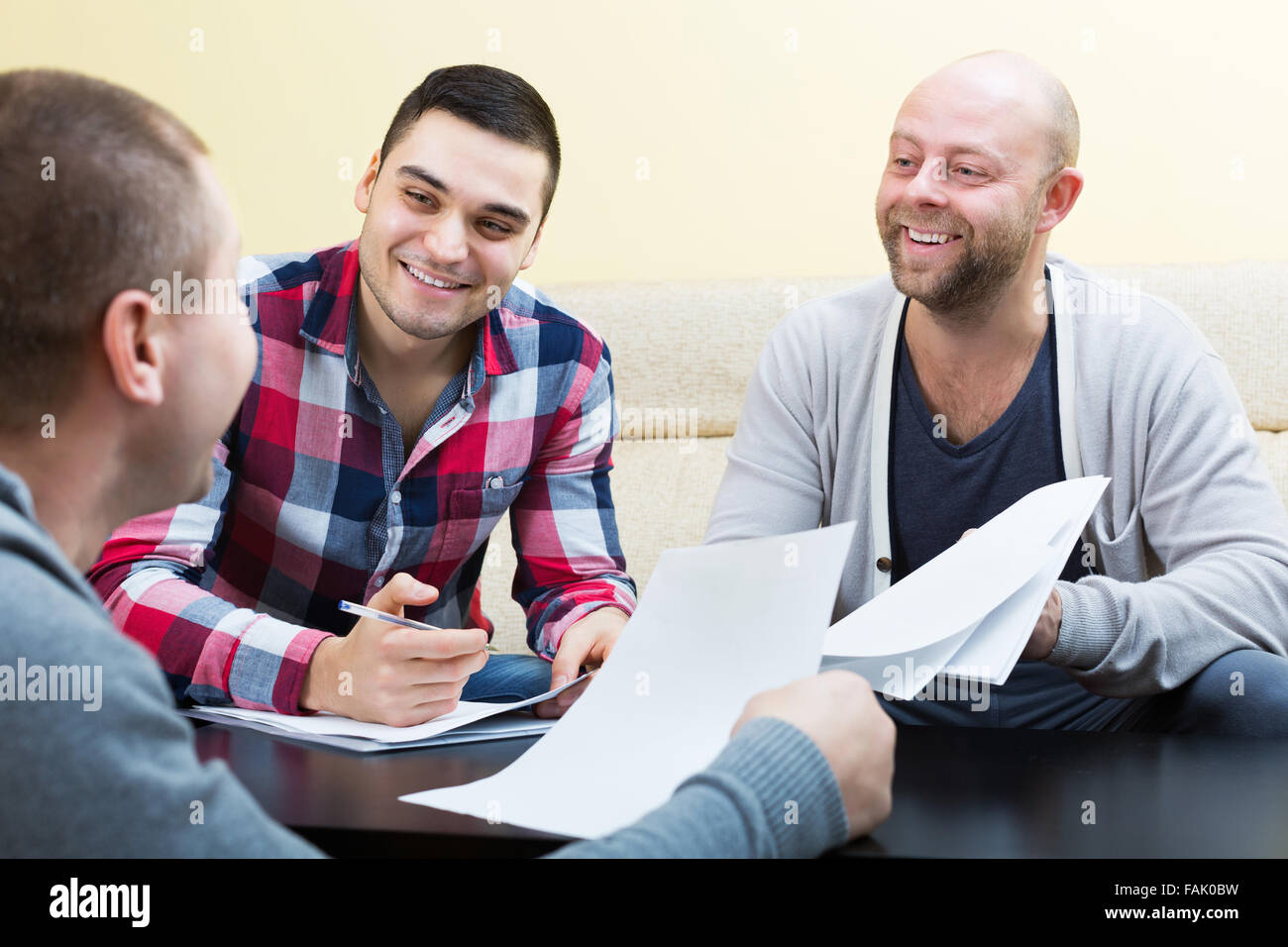 Satisfied adult clients sitting at the table with papers and smiling ...