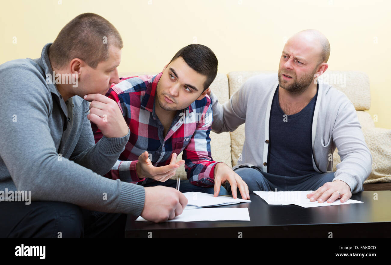 Guys sitting at the table with papers and sharing problems Stock Photo ...