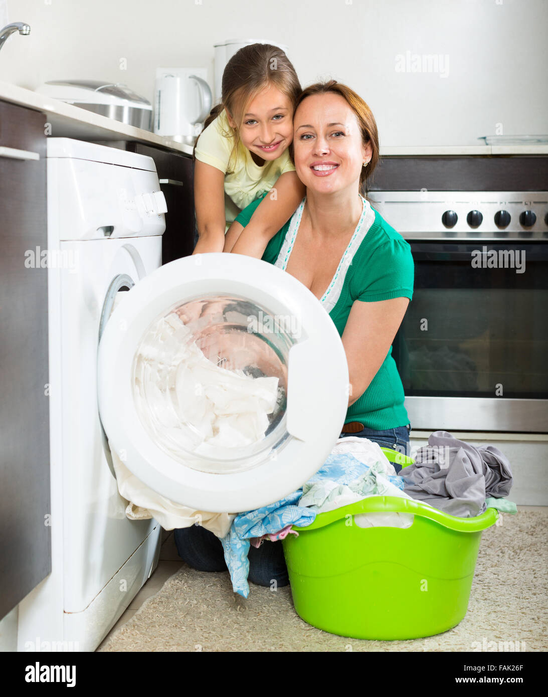Home laundry. Happy smiling woman with playful daughter using washing ...