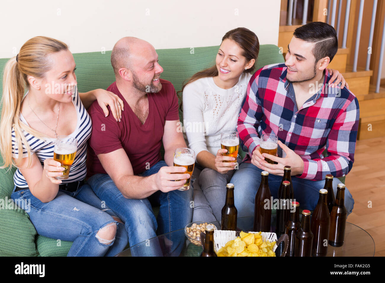 people drinking beer and laughing at home Stock Photo - Alamy