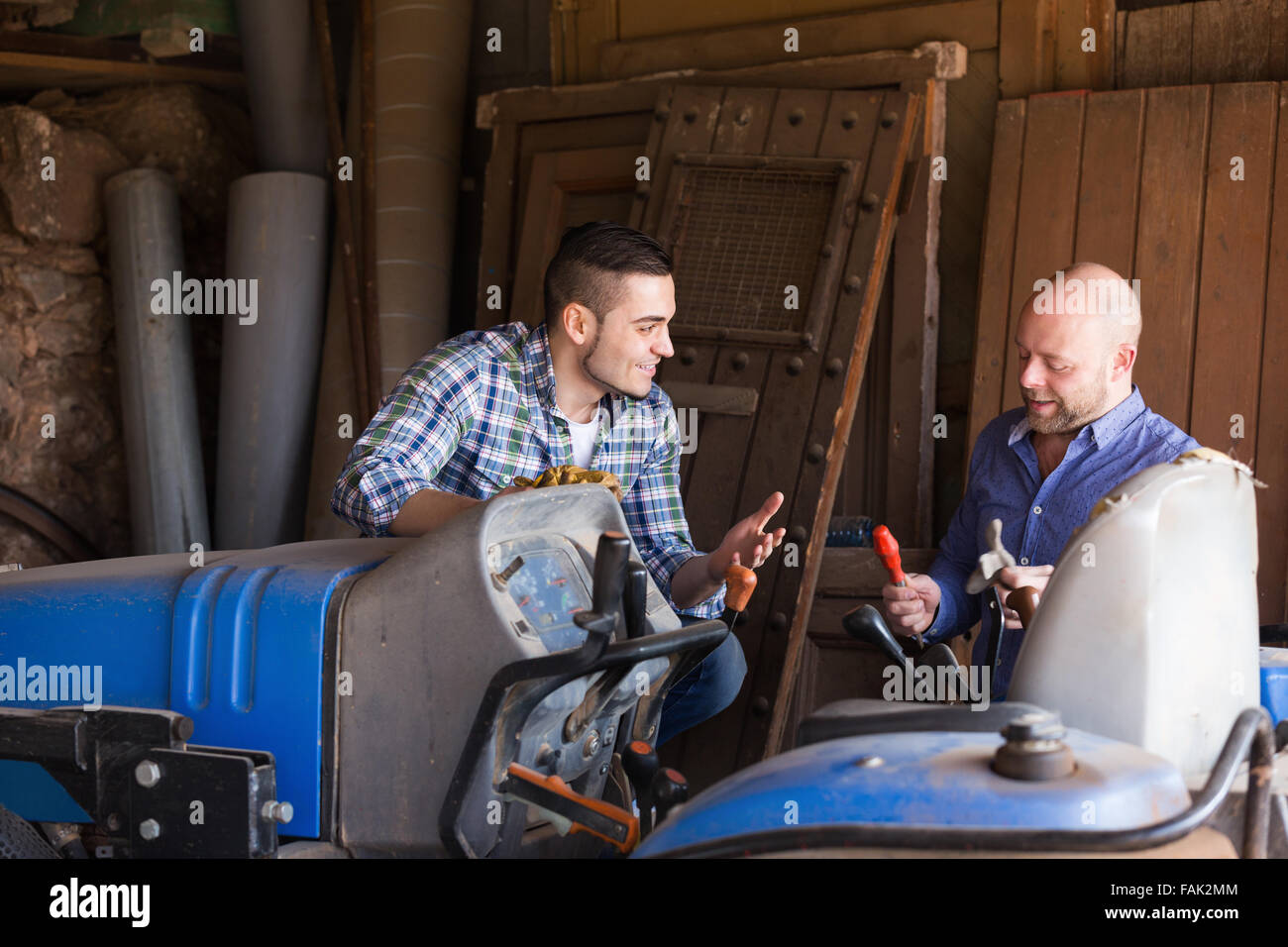 Two positive male drivers working with tractor and chatting Stock Photo ...