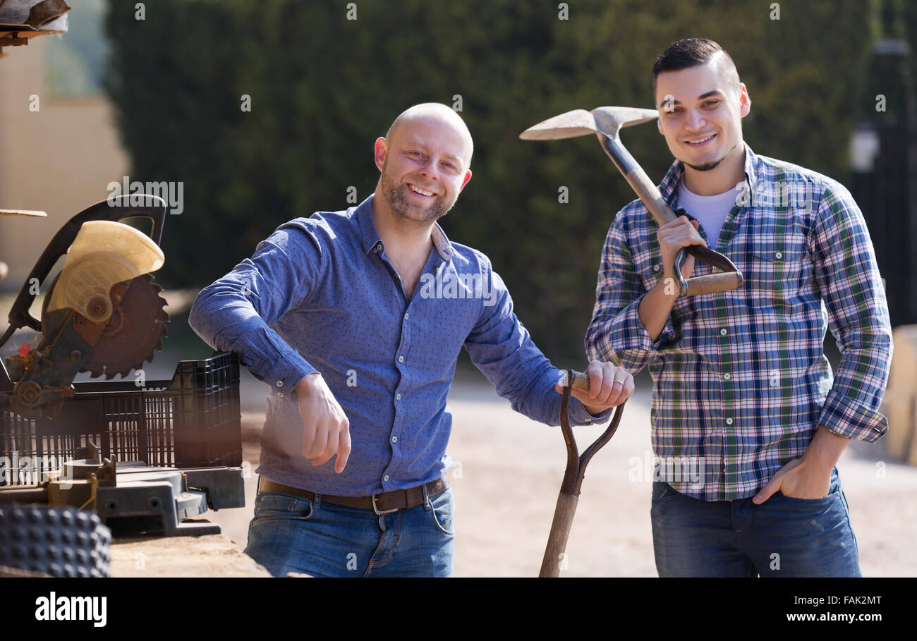 Two male farmers standing with spades at farmyard Stock Photo - Alamy