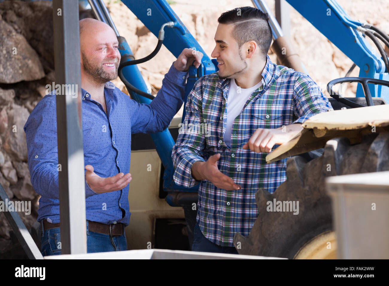 Two young male drivers working with tractor and chatting outdoor Stock ...