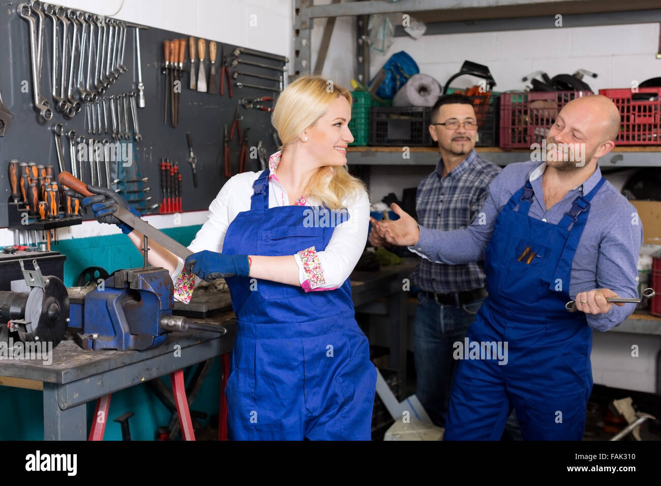 two happy workers and adult superviser at auto repair shop. Focus on ...