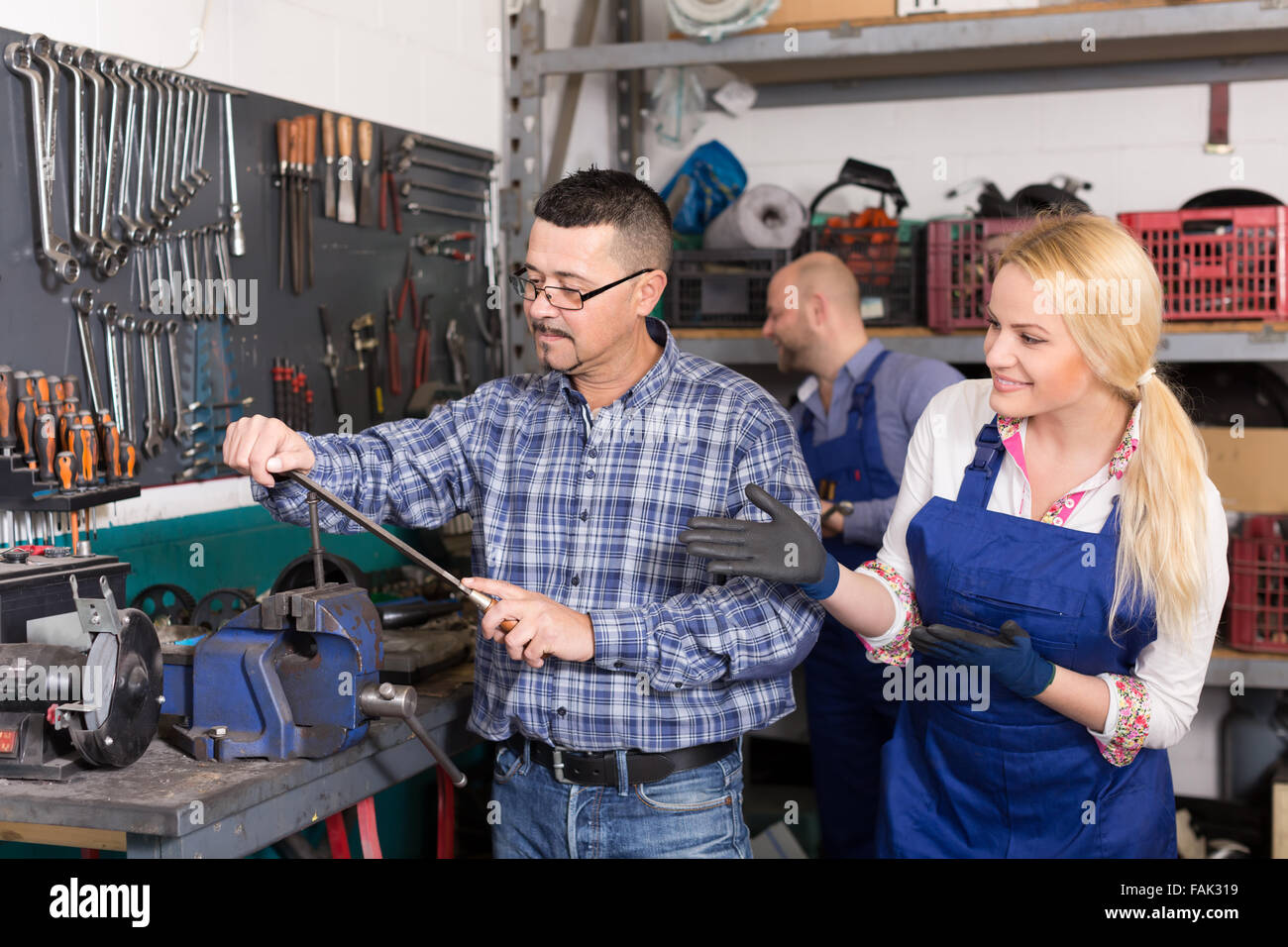 Positive auto mechanics chatting with client at workshop and smiling ...