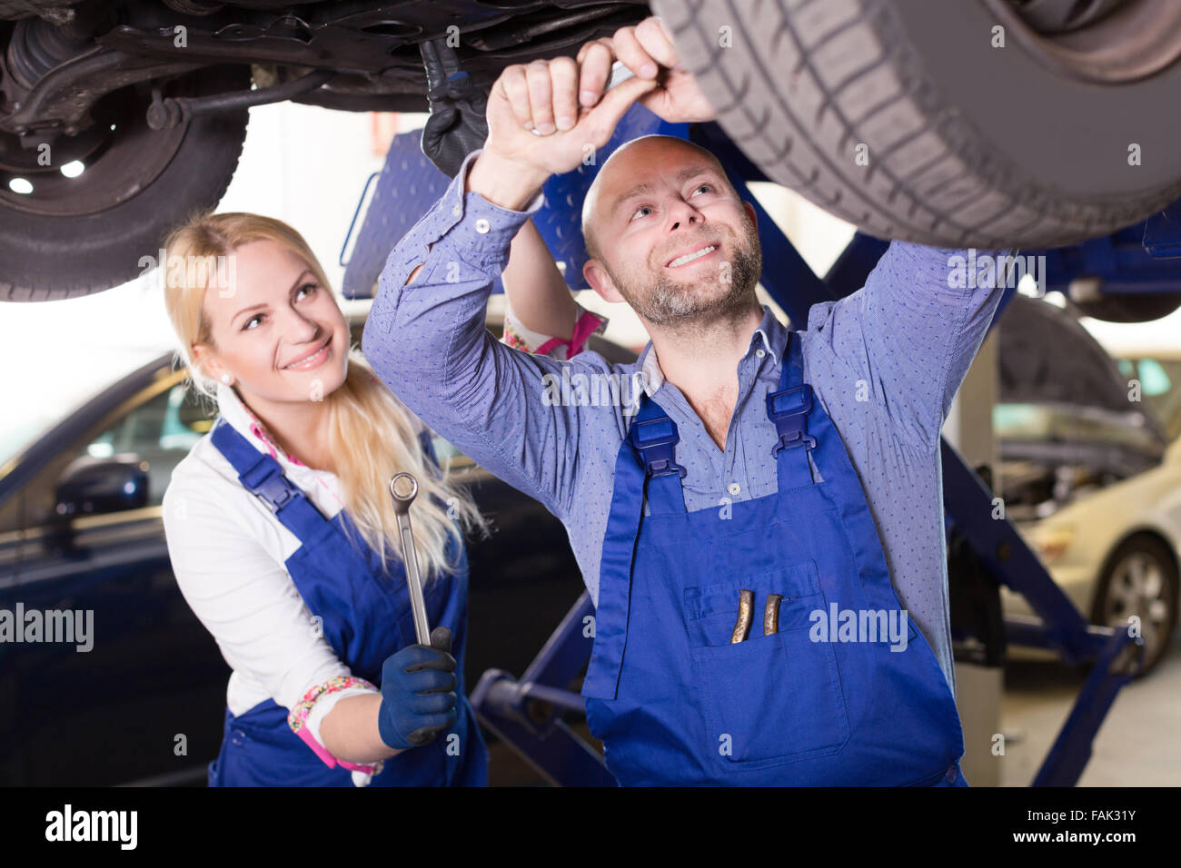 Handsome russian mechanic and female assistant working at auto repair ...