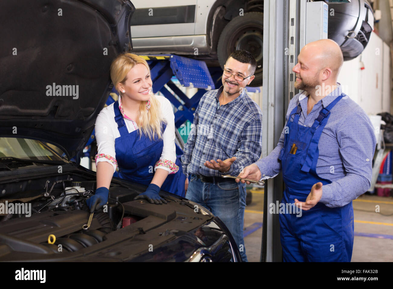 Smiling service crew and satisfied driver standing near car. Focus on ...