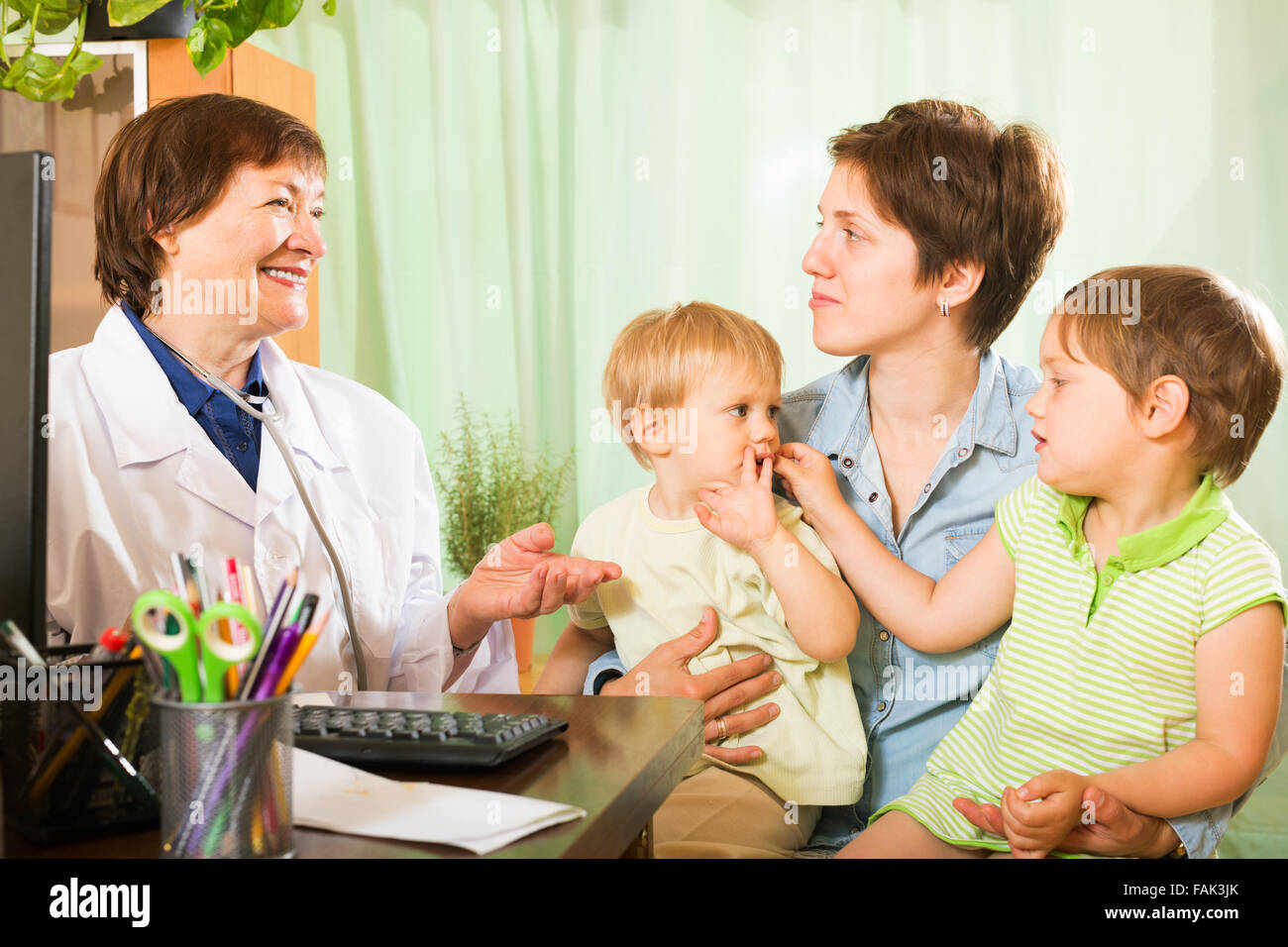 Young mother with children and friendly pediatrician doctor at clinic ...