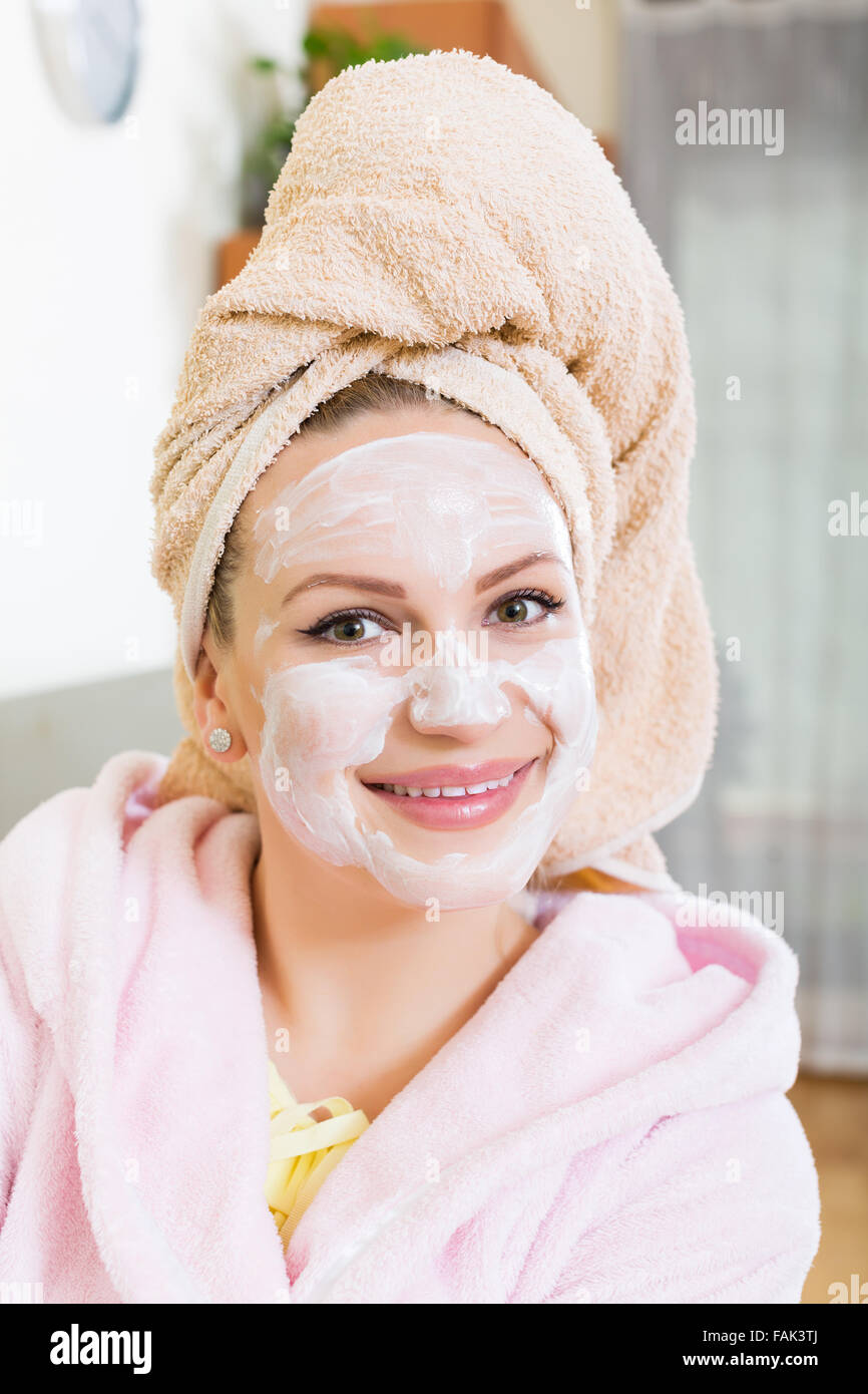 Portrait of smiling girl lying on couch with cream over face indoors ...